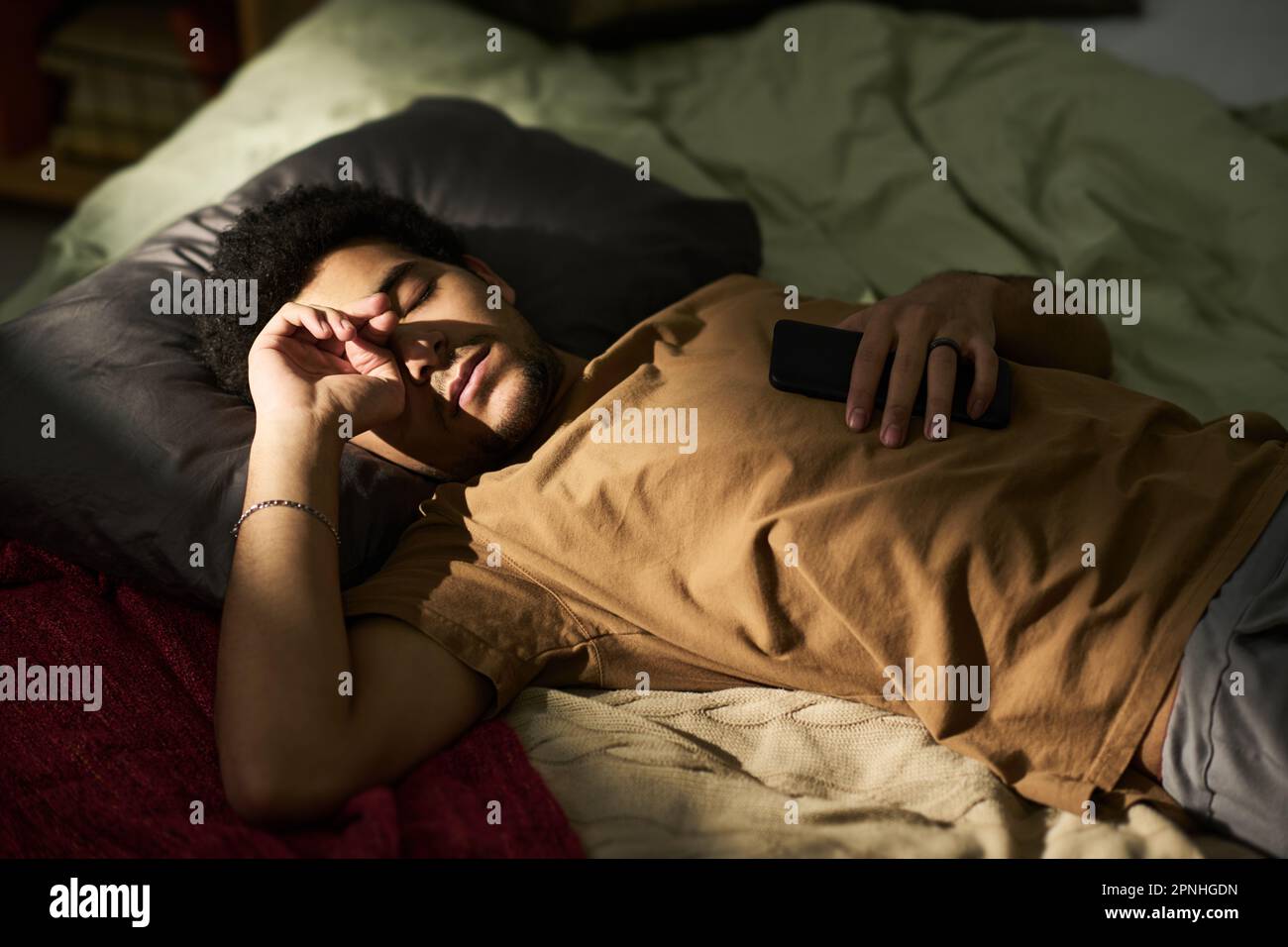 High angle view of young tired man lying on bed and sleeping in the ...