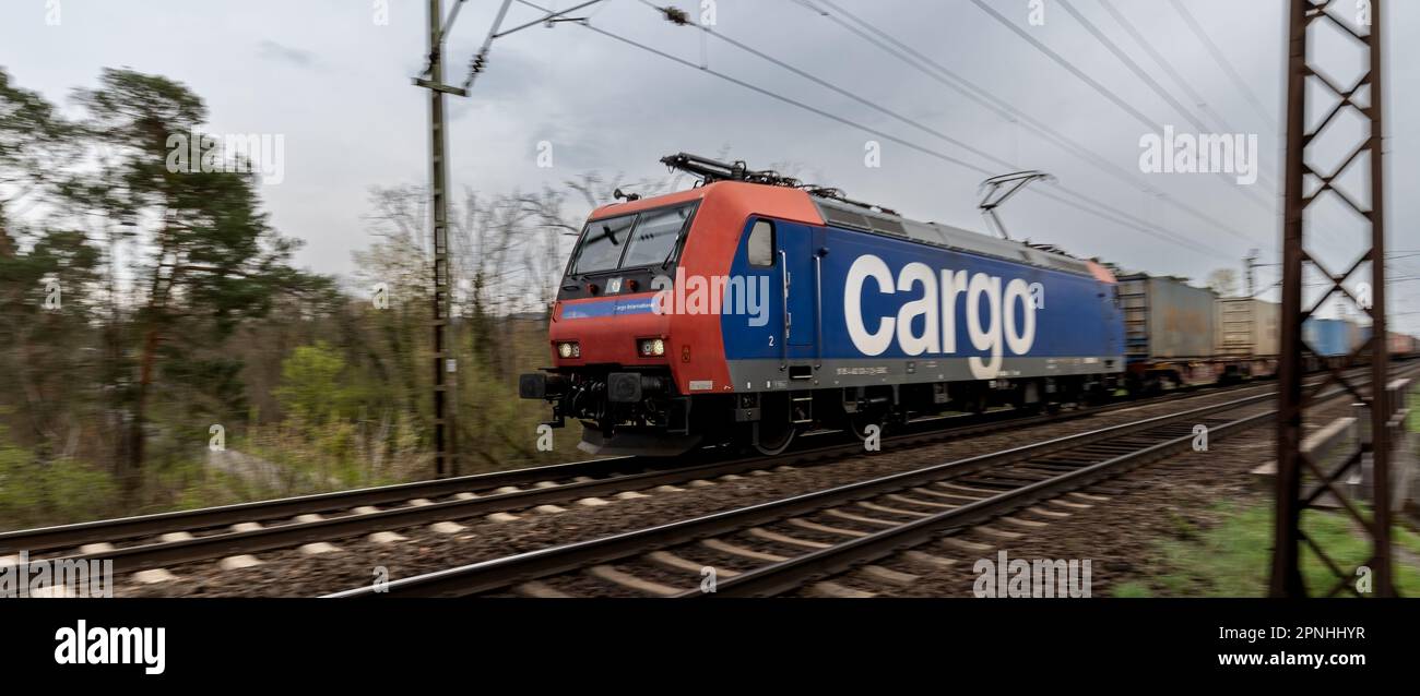 A freight train travelling along a set of tracks, with electrical power ...