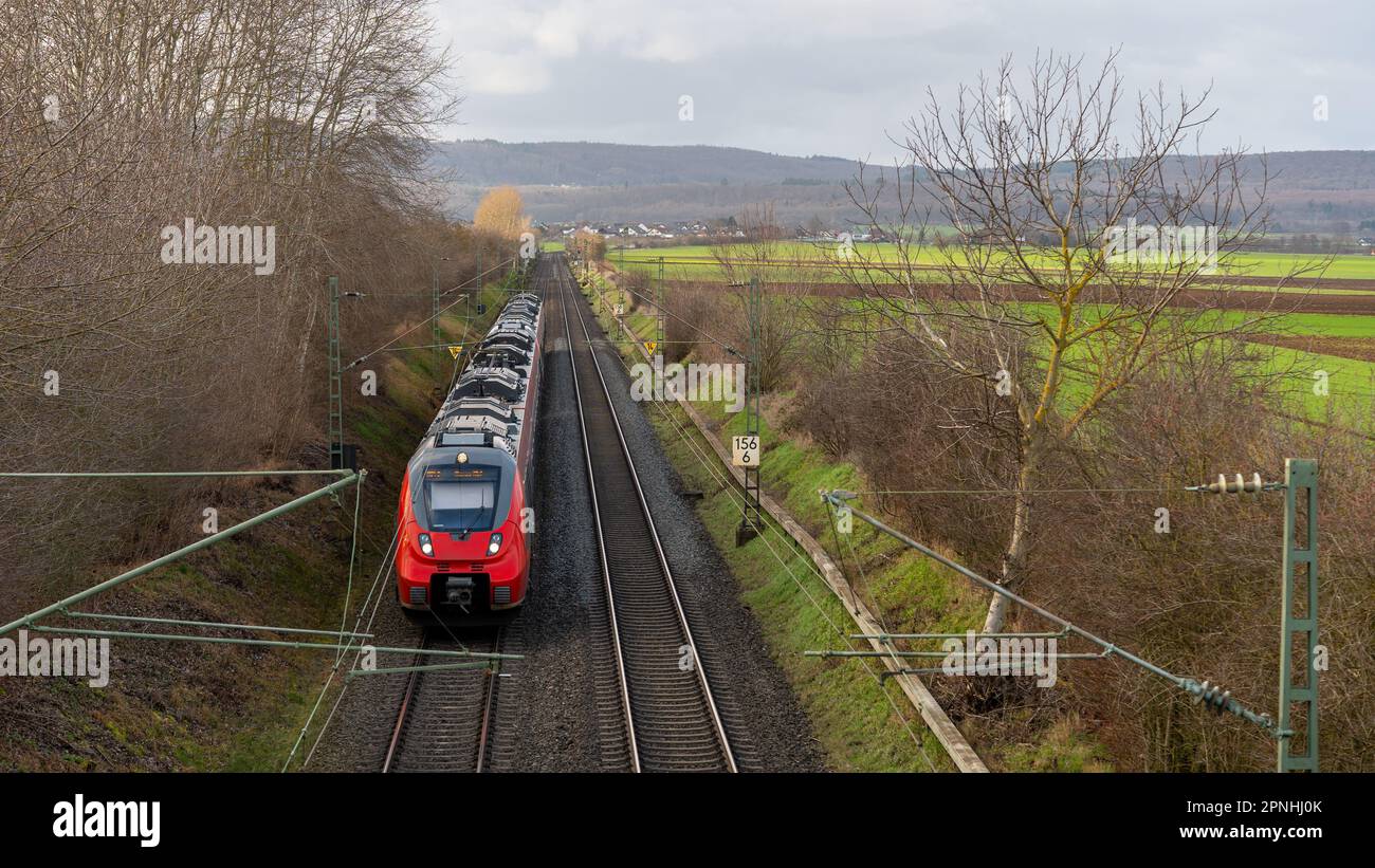 A red train traversing a set of railway tracks, moving along the ...