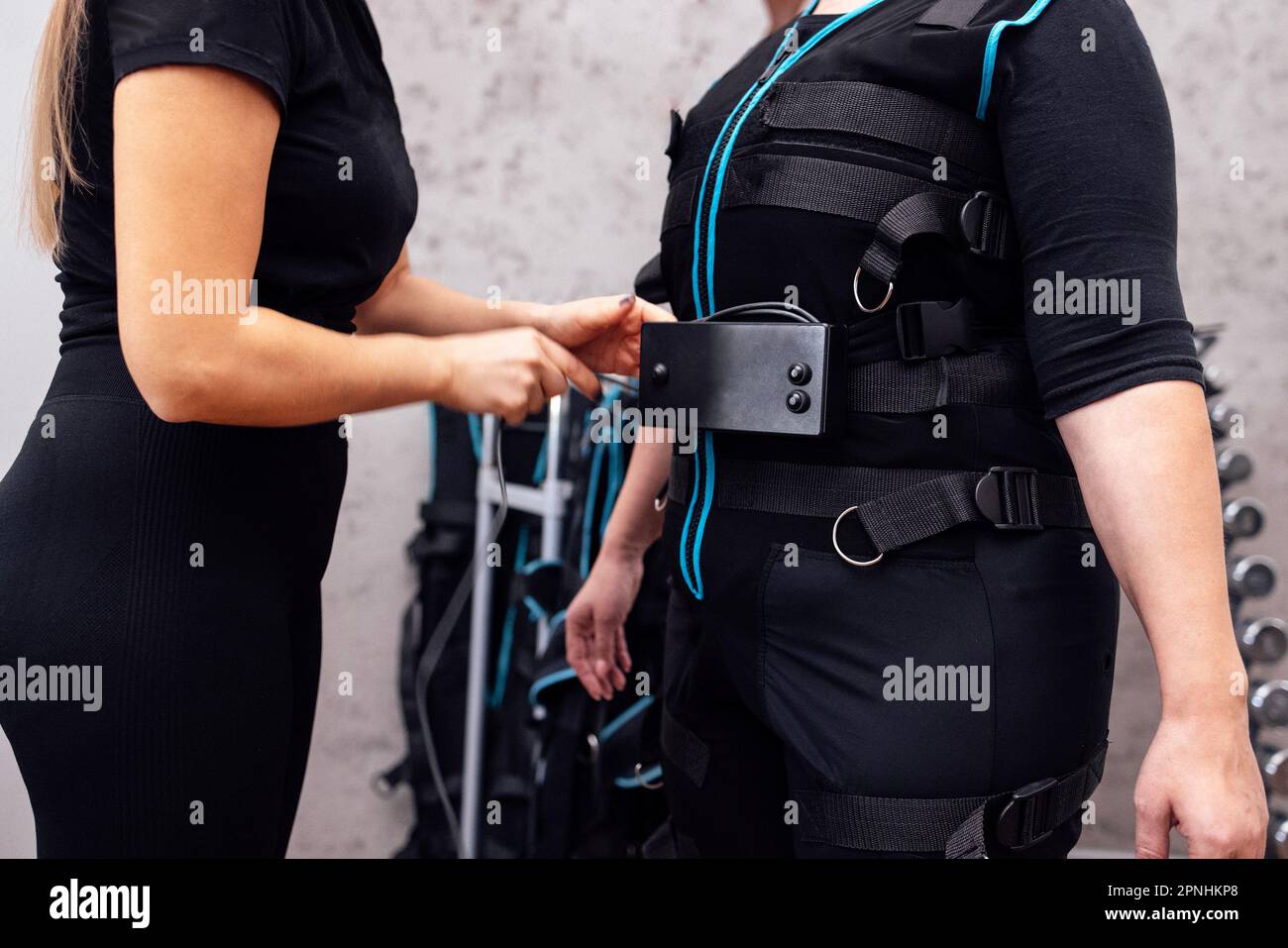 Female coach puts on suit for ems workout on senior woman. The trainer ...