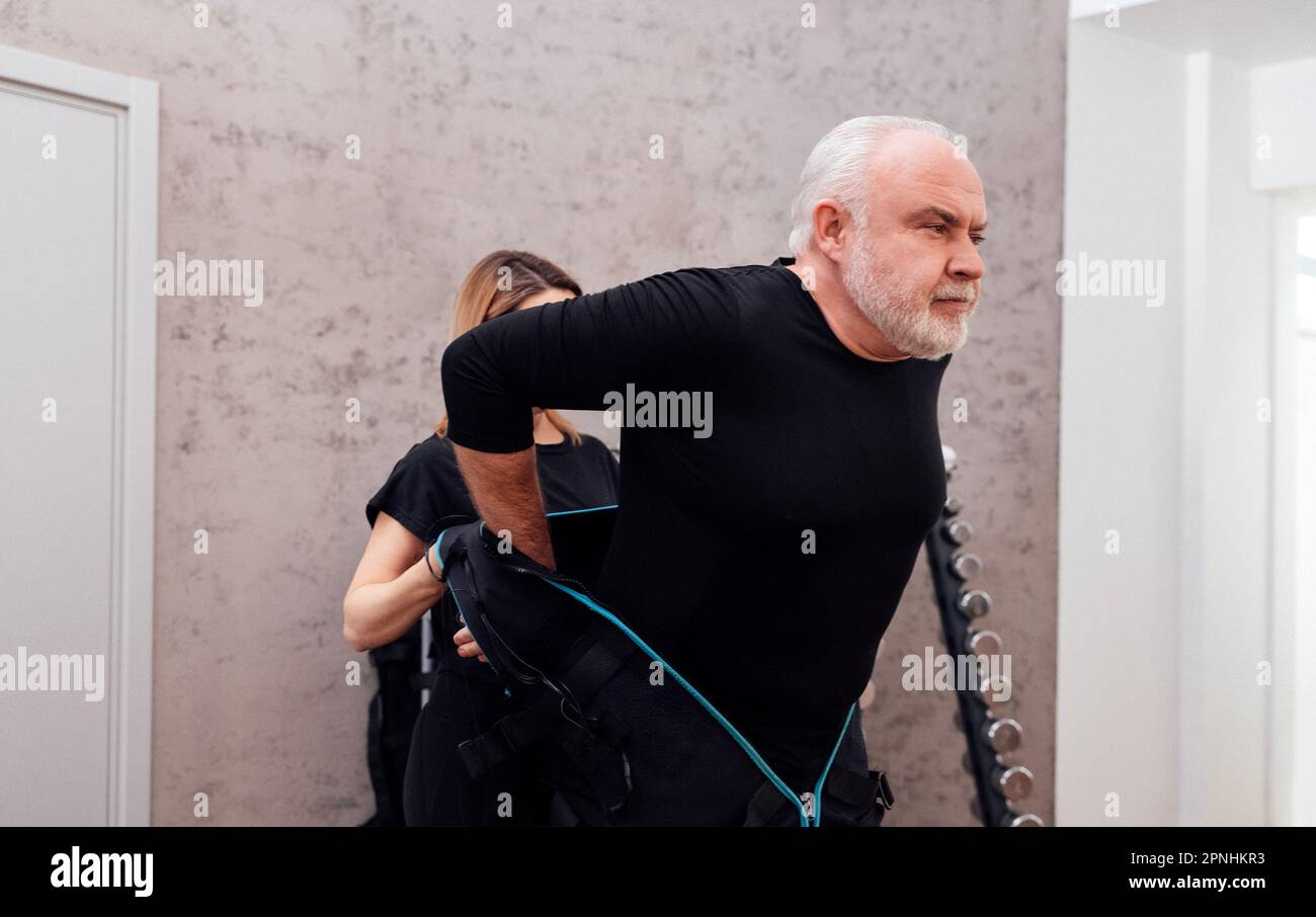 Female trainer fixes the necessary equipment on ems suit to male client ...