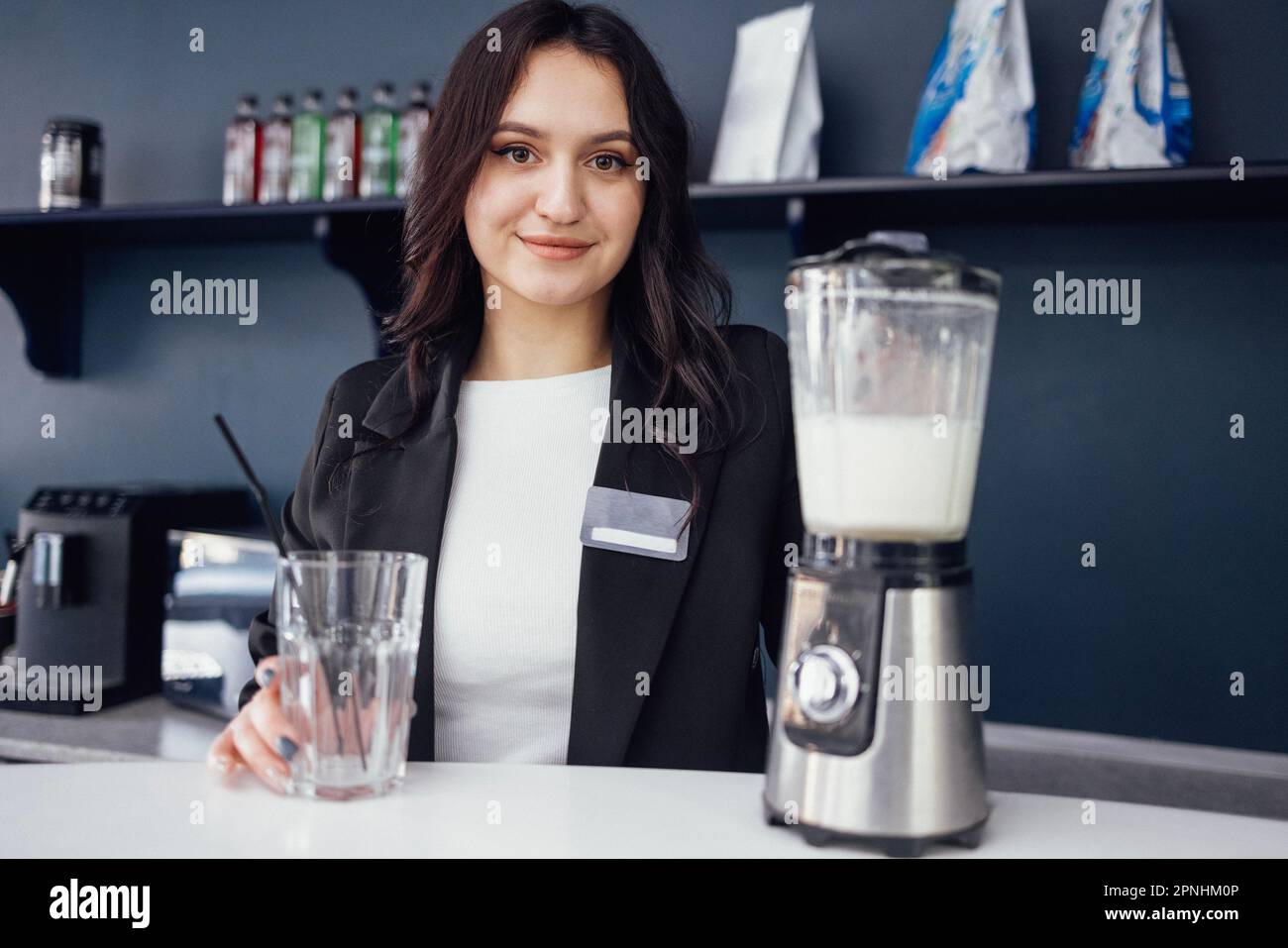 Young pretty woman prepares protein shake using stationary blender ...