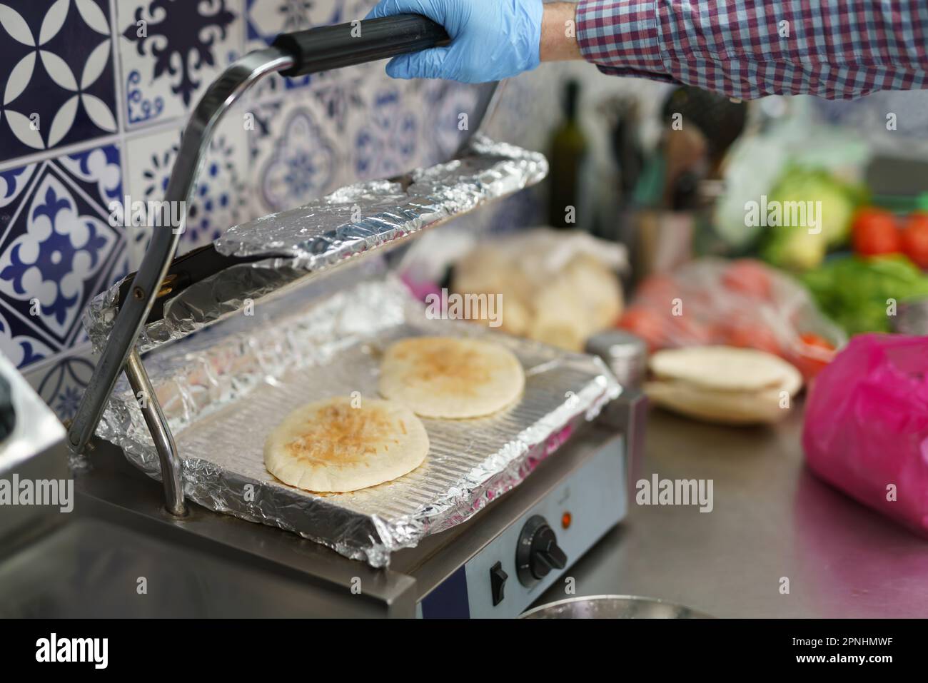 The cook preparing pita bread on a electric grill in a commercial ...
