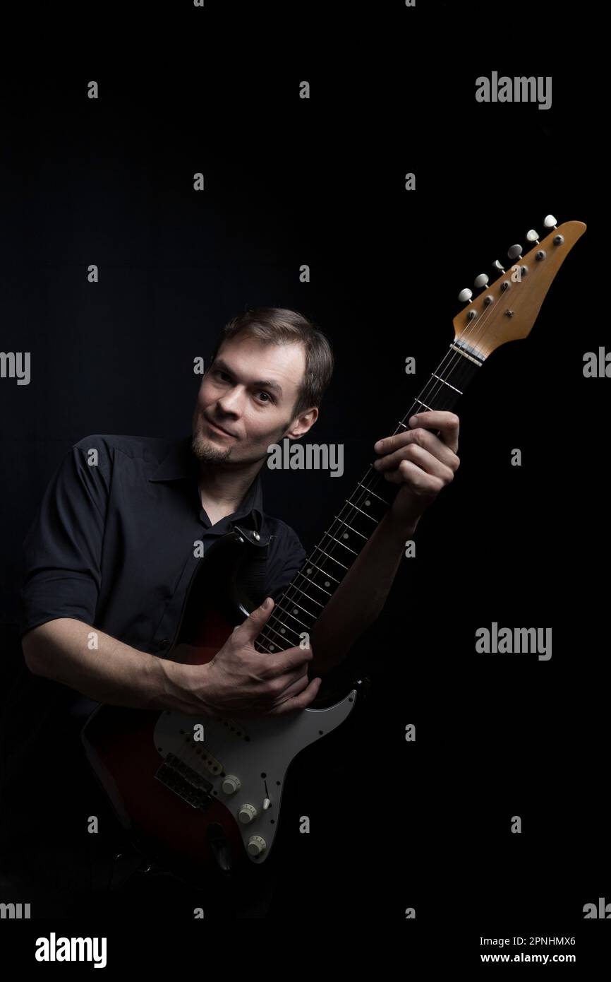 Caucasian man guitarist playing on electric guitar on black background ...