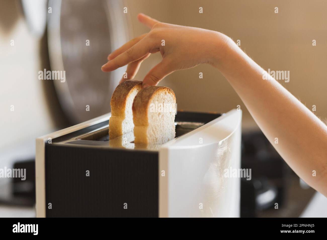 Close-up of a child's hand that inserts white slices of bread into a ...