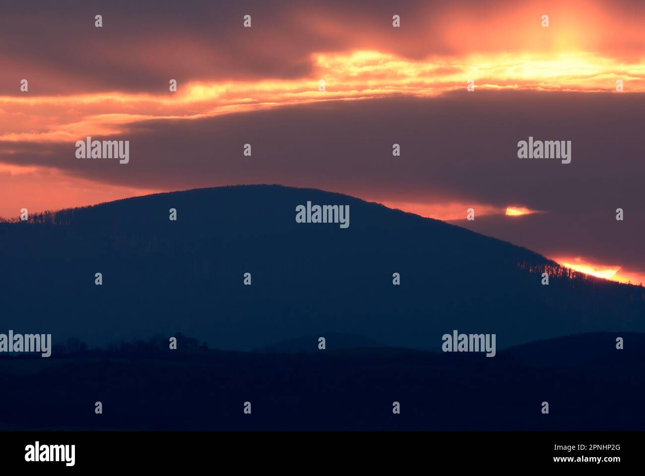 Disc of the sun setting behind a hill at sunset. Beautiful orange ...