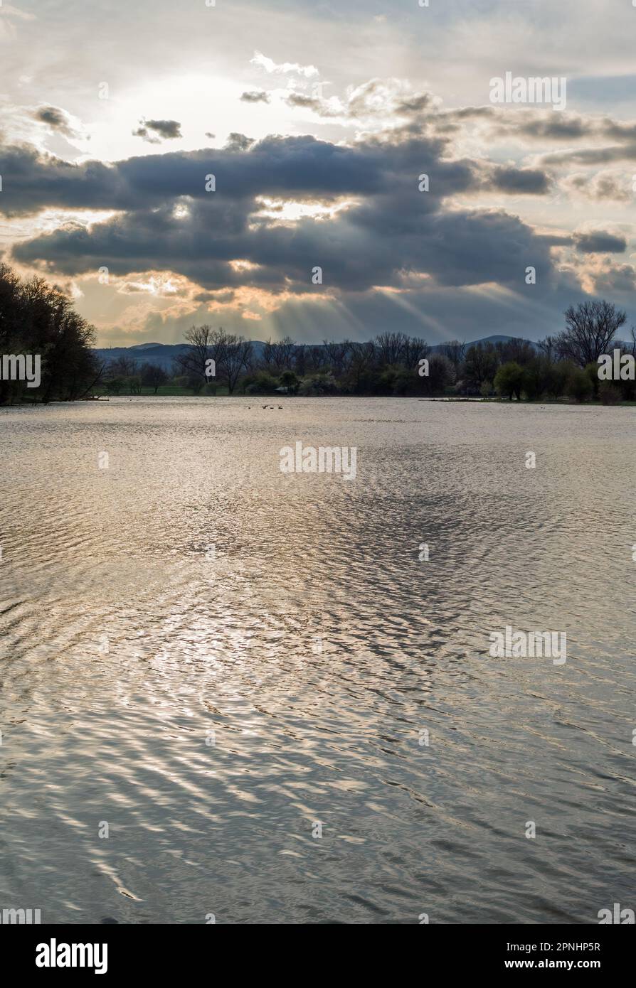 Lake with beautiful ripples in windy weather at sunset, sun rays ...
