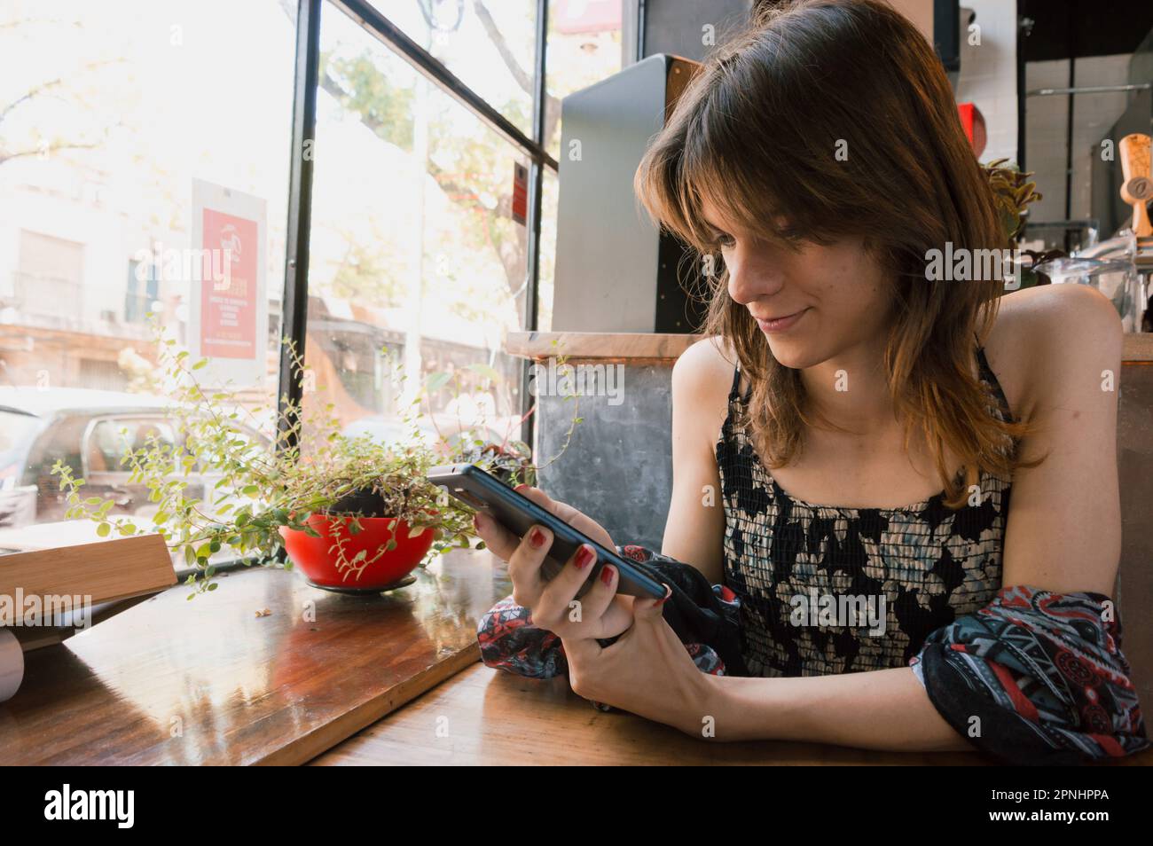 Latina transgender woman alone, sitting using the phone sitting in a ...