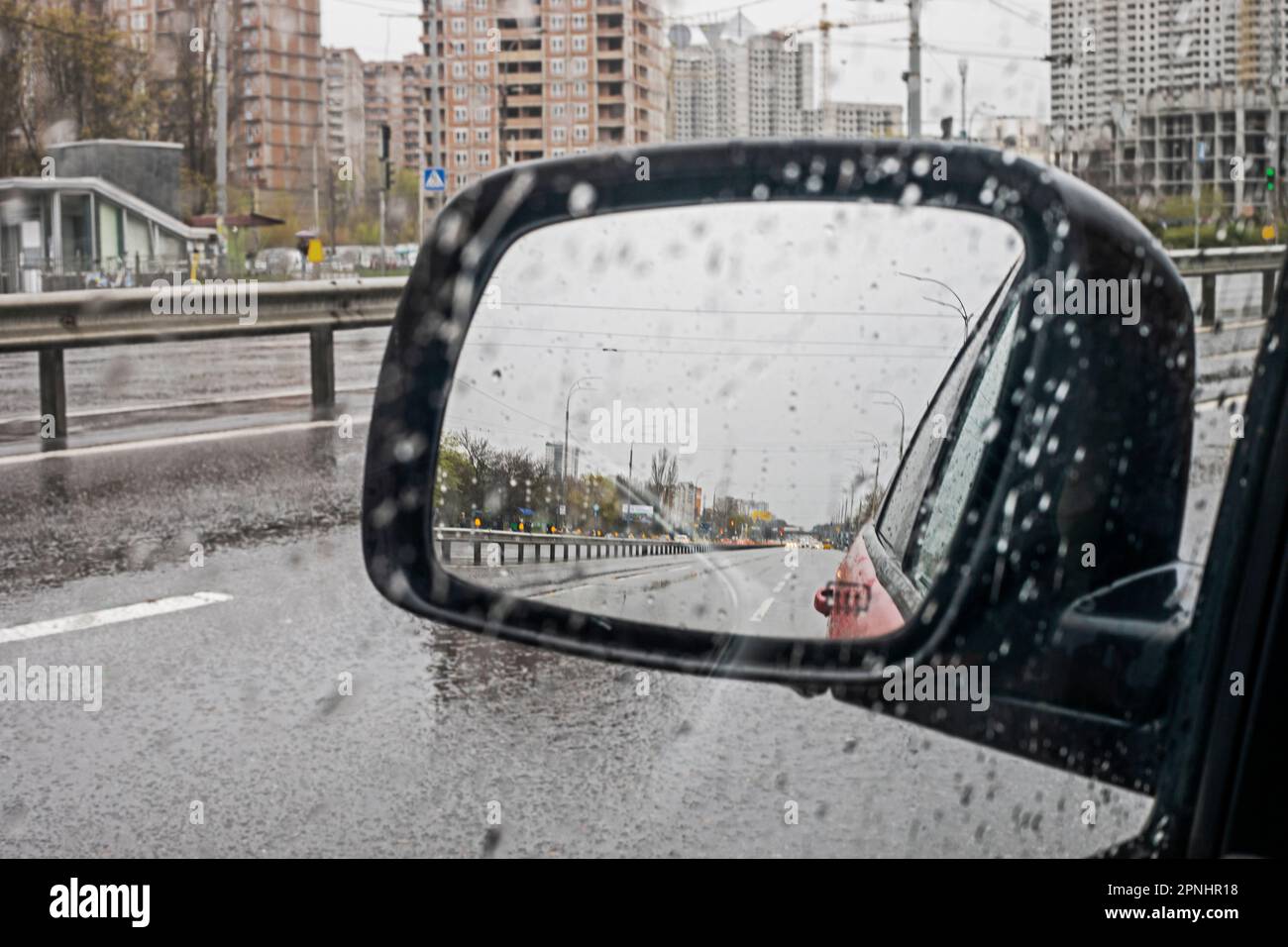 right mirror of the car in raindrops, poor visibility on the road ...