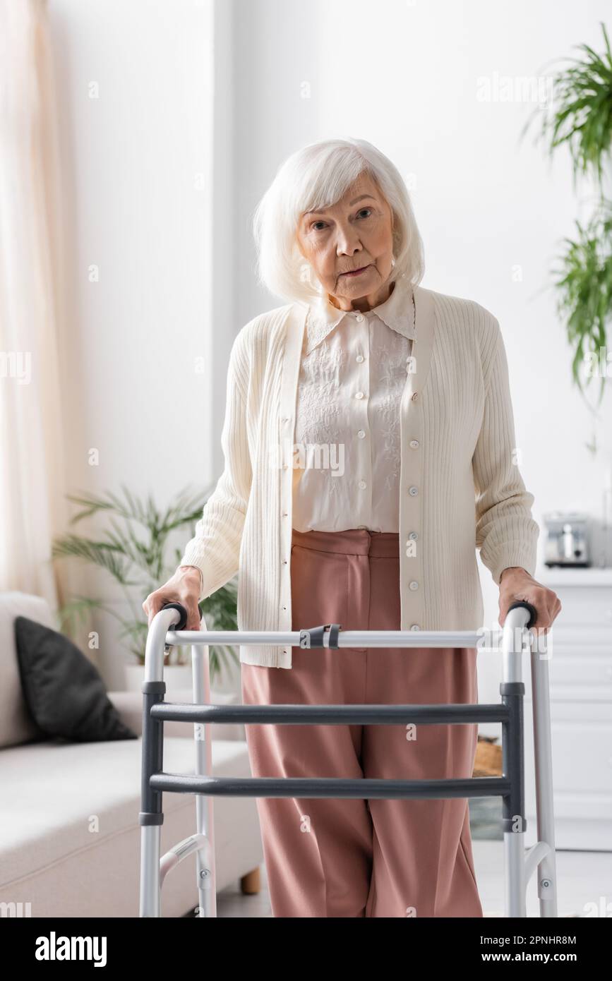 retired woman with grey hair walking with help of walker at home Stock ...