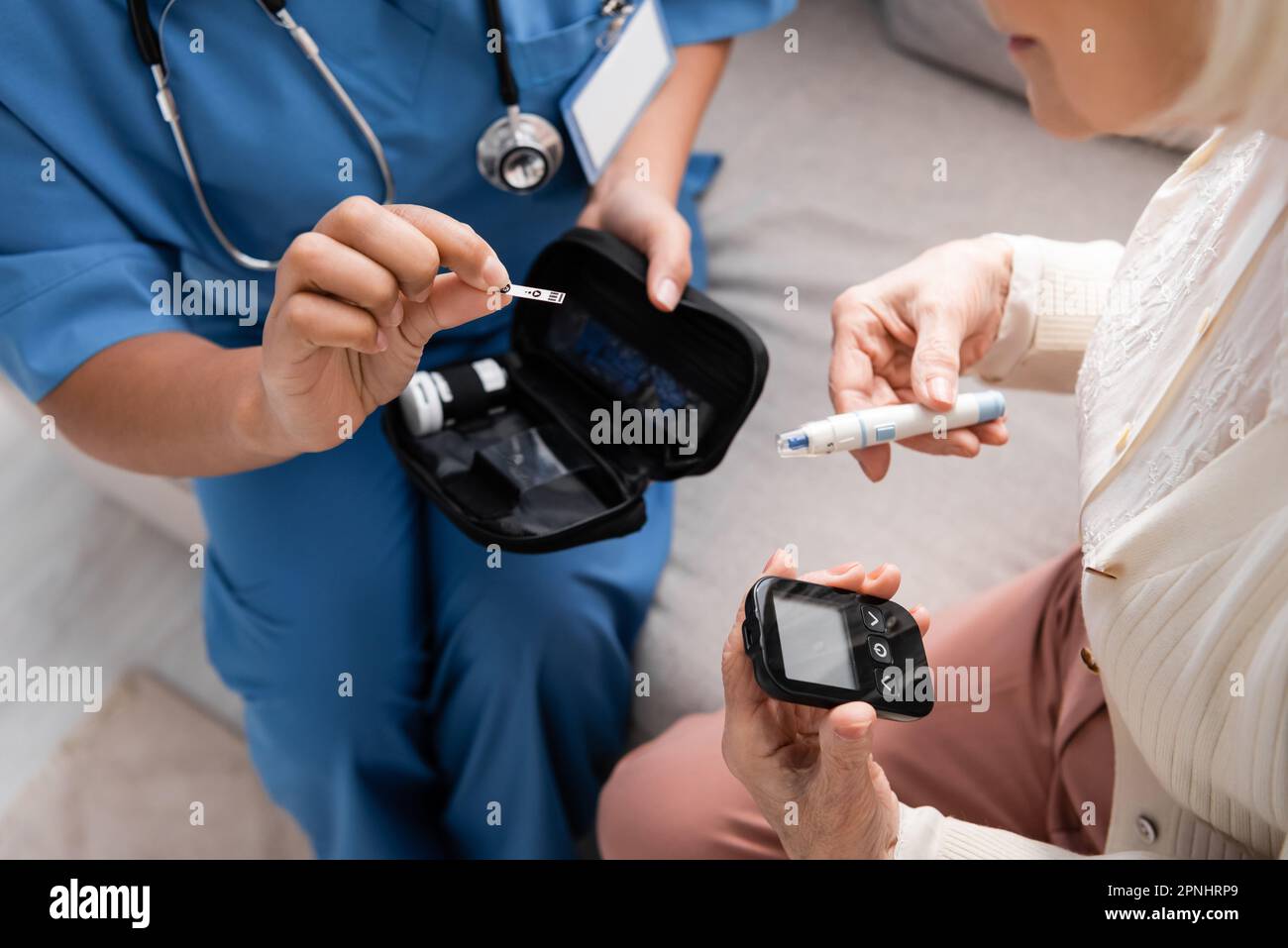 cropped view of multiracial nurse in uniform holding test strip near ...