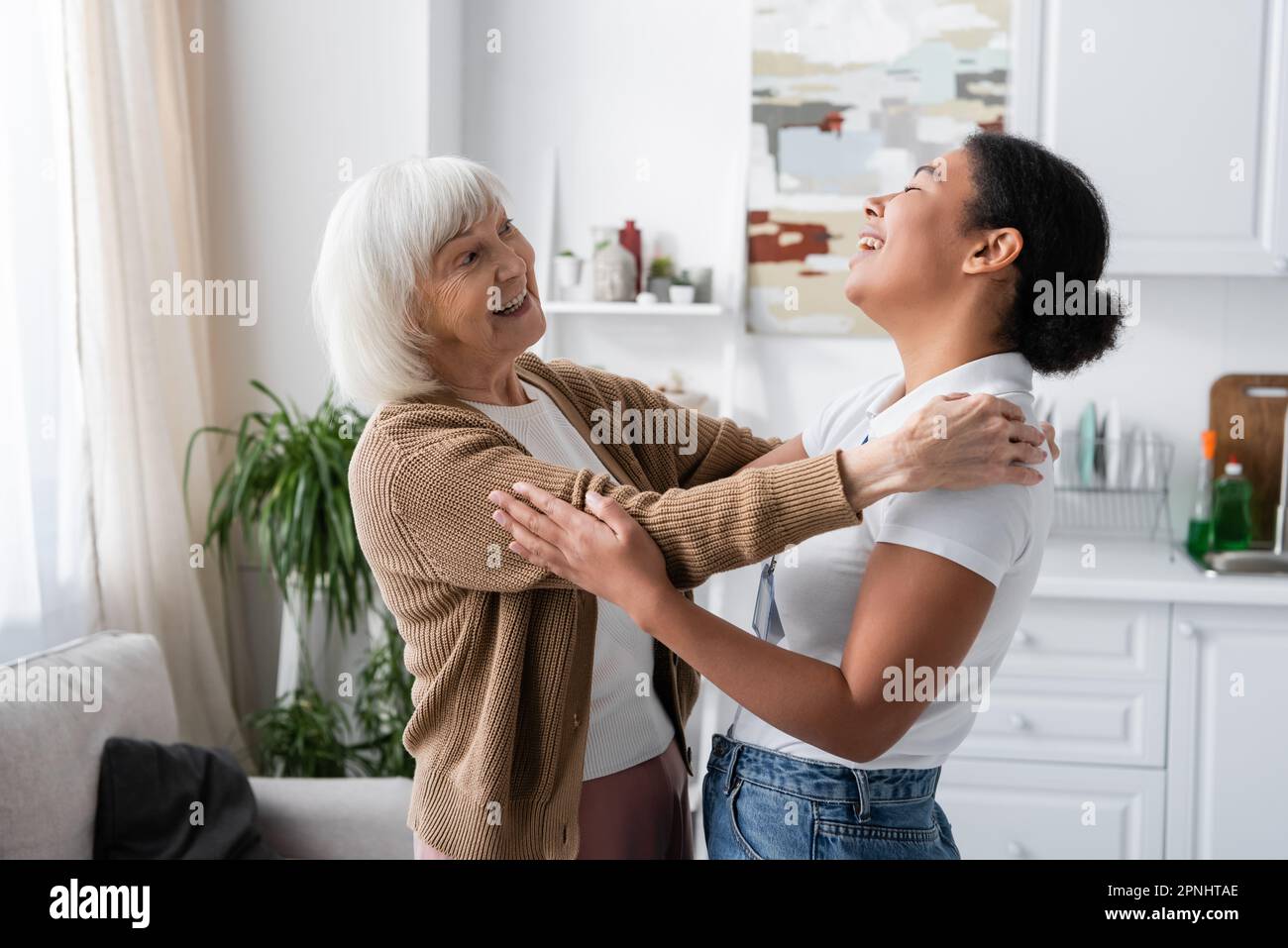 positive multiracial social worker and senior woman laughing and ...