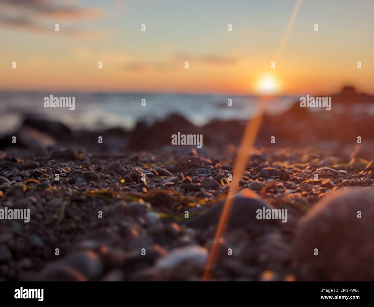 A tranquil beach scene at sunset featuring a golden sun sinking slowly ...