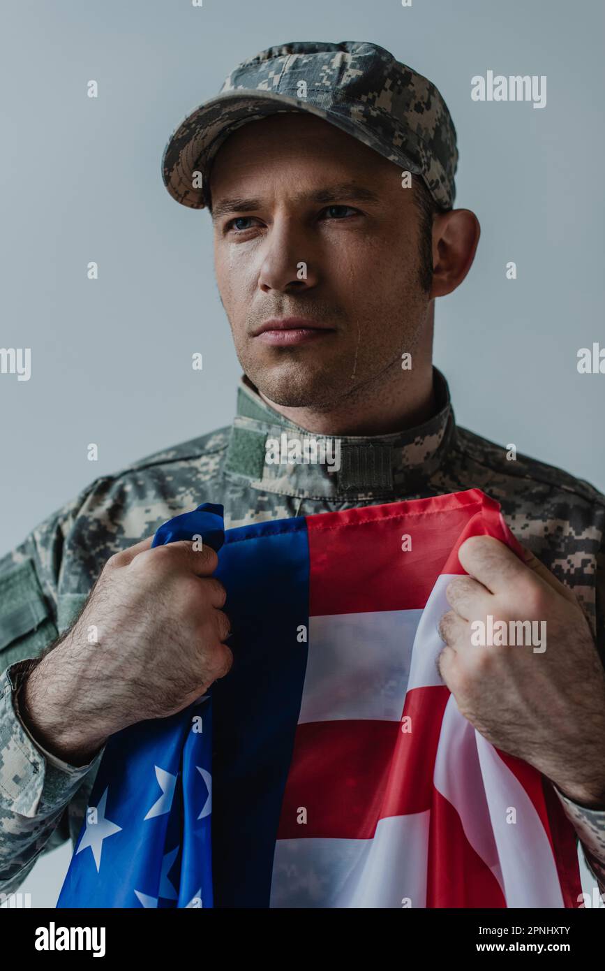 upset American soldier holding flag of United States while crying ...
