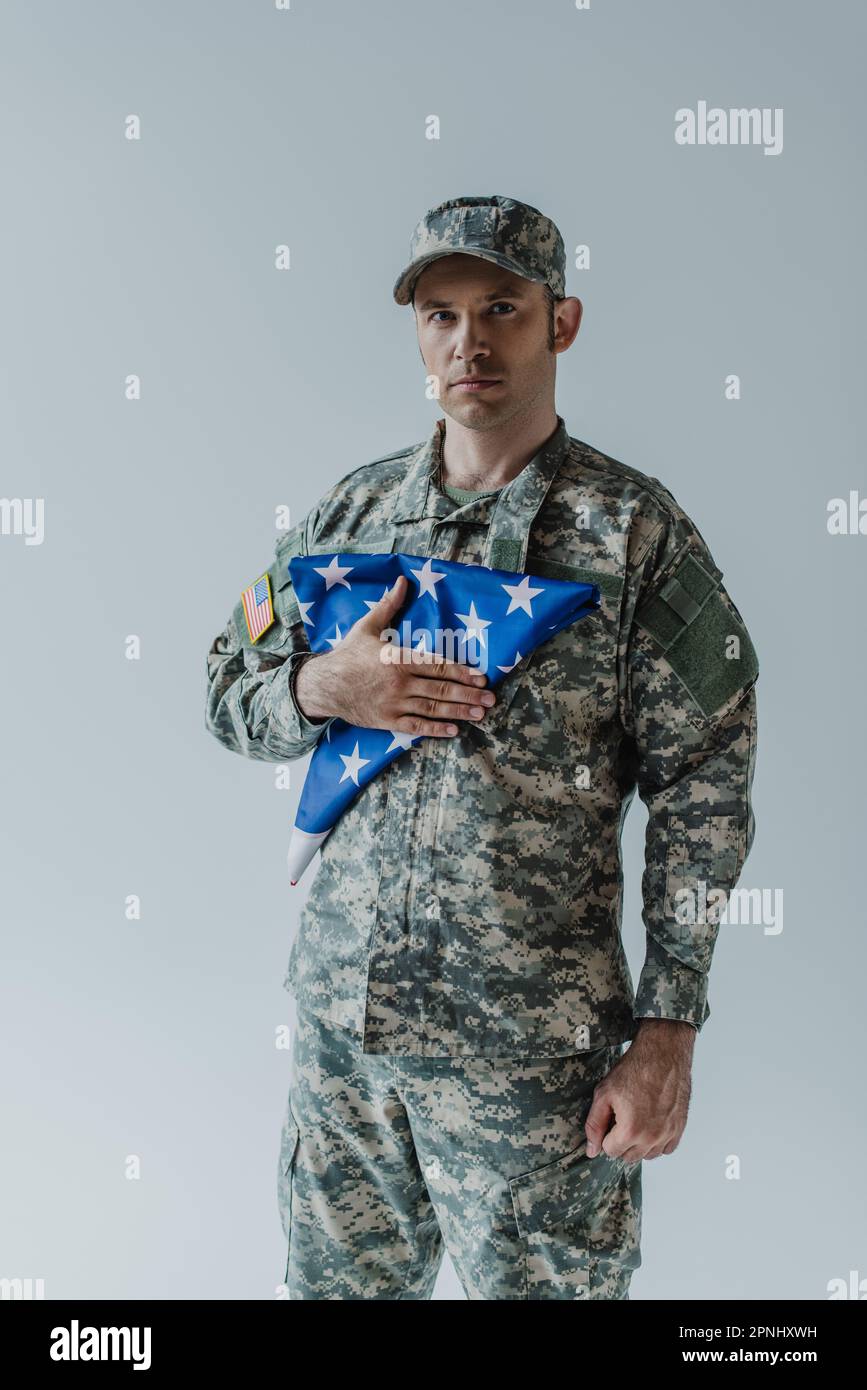 good looking soldier in military uniform holding folded flag of United ...