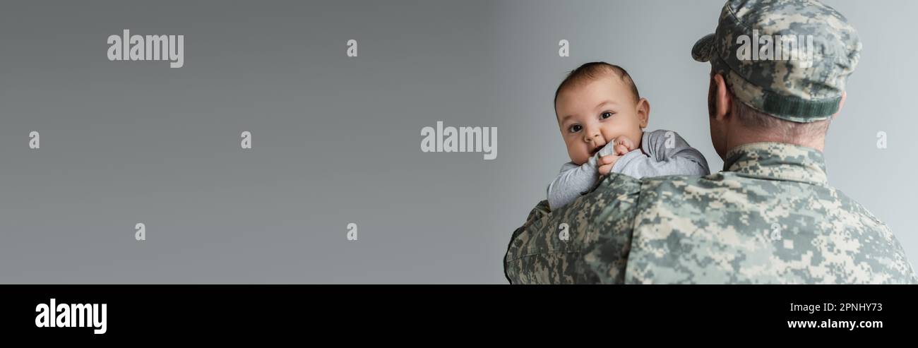 serviceman in military uniform and cap hugging newborn son isolated on ...