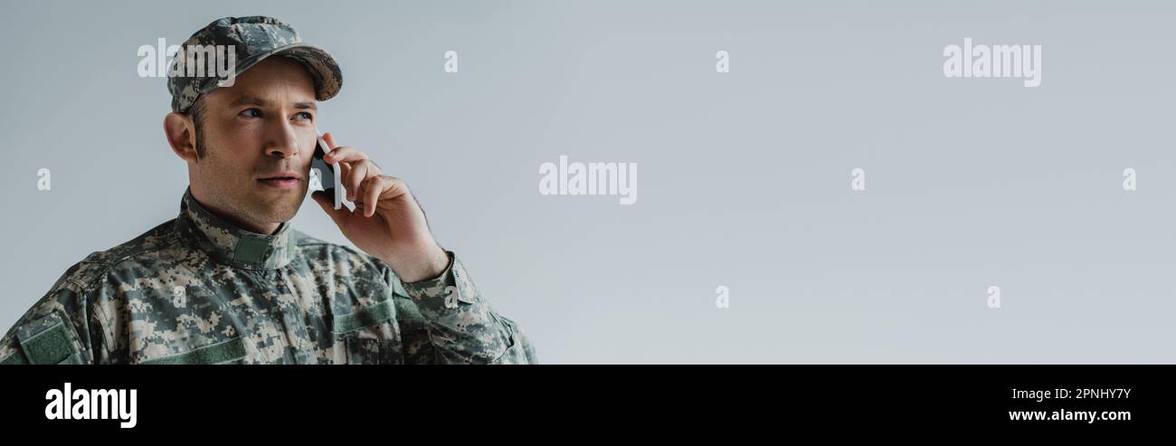 serviceman in cap and army uniform having conversation on smartphone ...