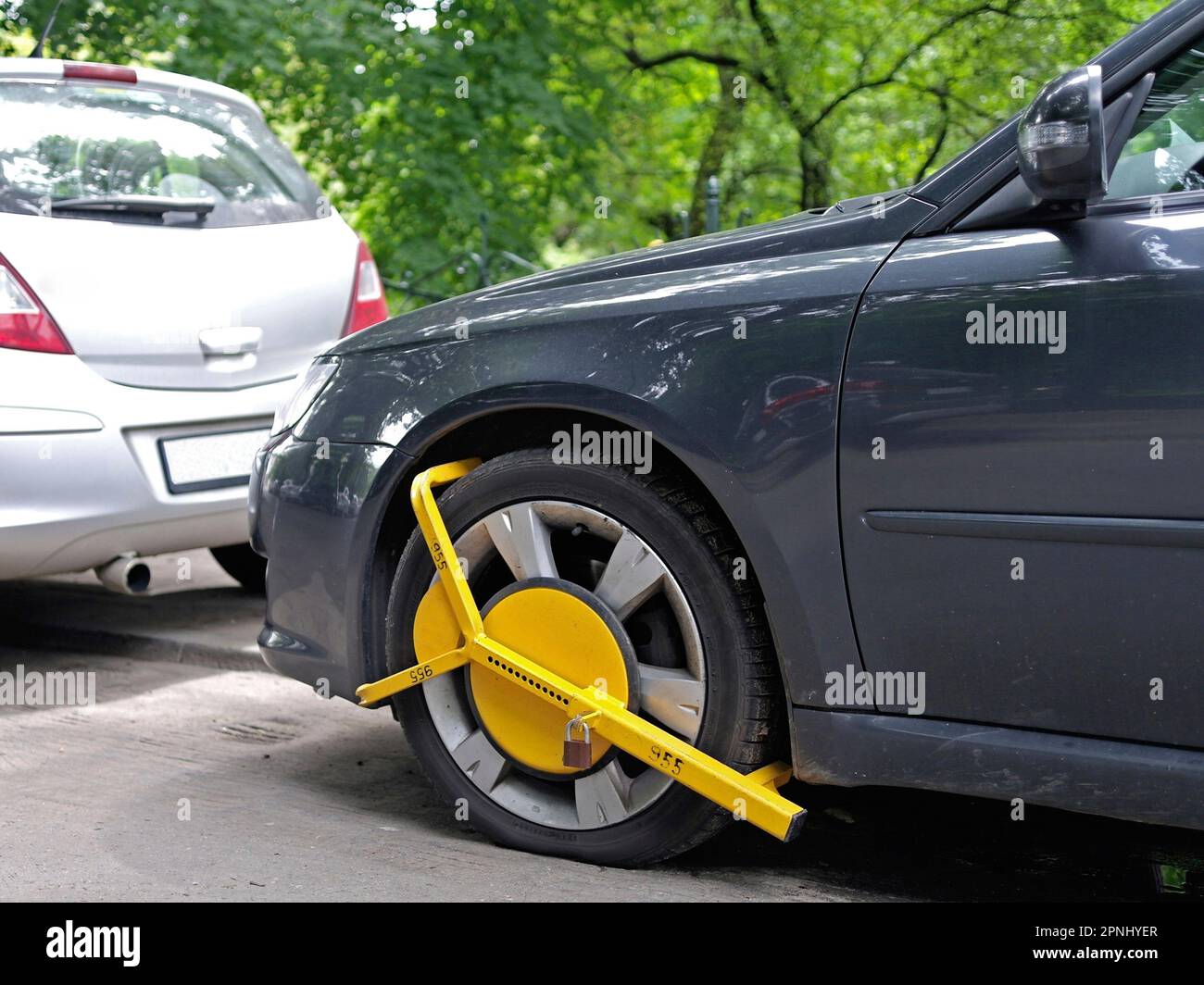 Wheel clamp mounted on grey wrong parking car Stock Photo - Alamy