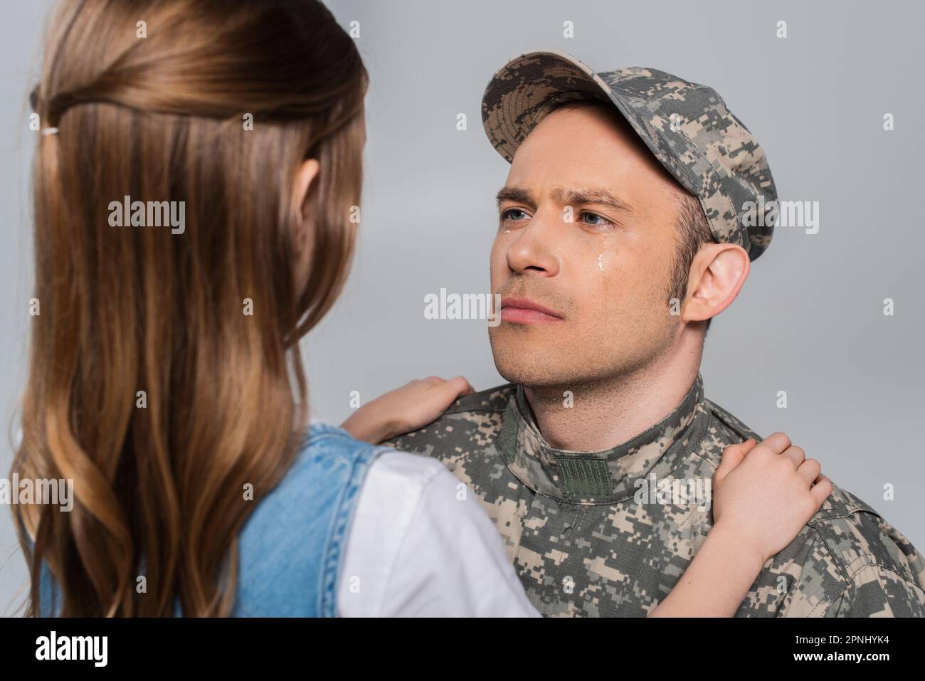 sad serviceman in military uniform crying and looking at daughter ...