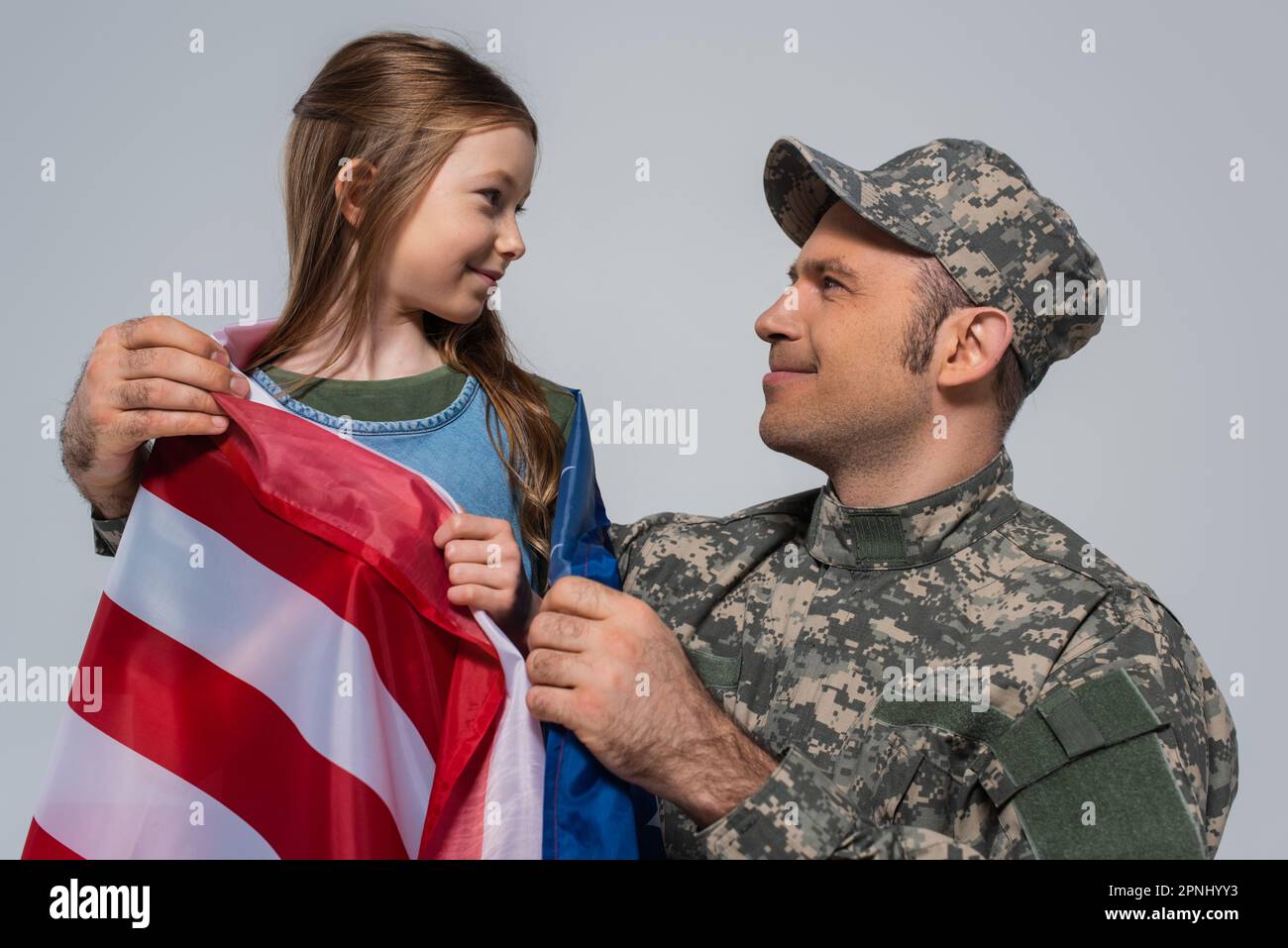 serviceman in military uniform looking at happy daughter wrapped in ...