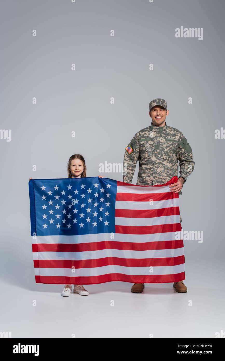 serviceman in military uniform holding flag of United States with happy ...