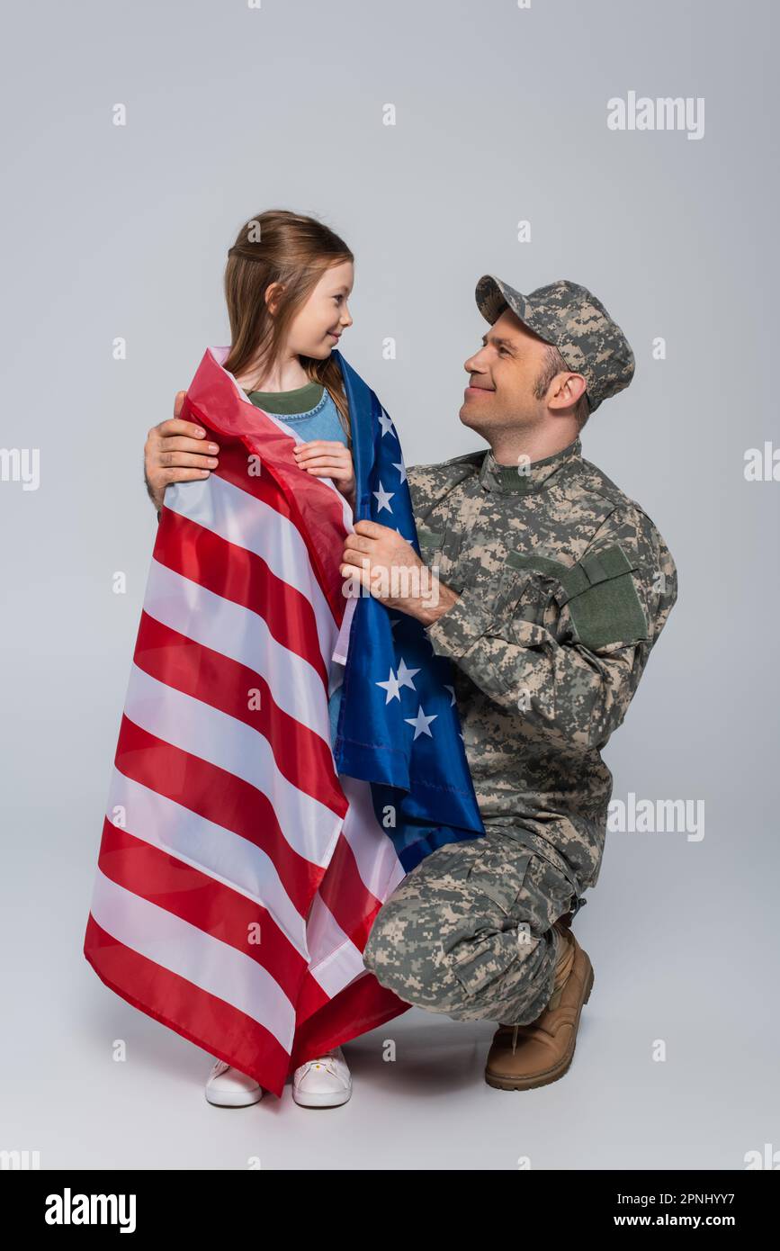 happy serviceman in military uniform looking at daughter wrapped in ...