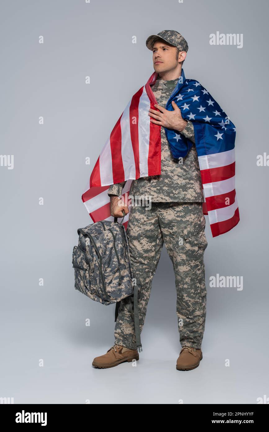patriotic army soldier in camouflage uniform wrapped in flag of United ...