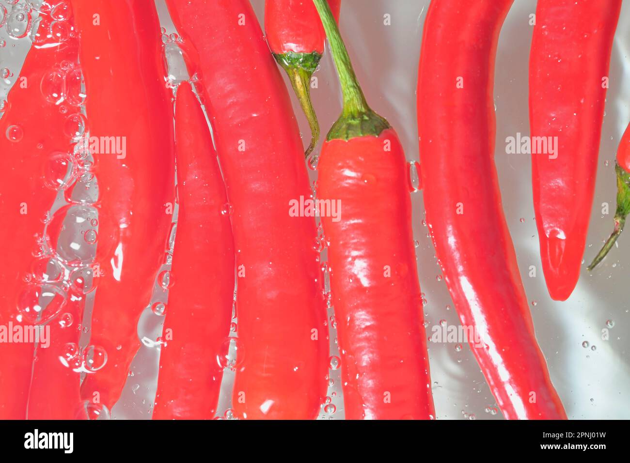Close-up of fresh slices chilli peppers on white background. Red chilli ...