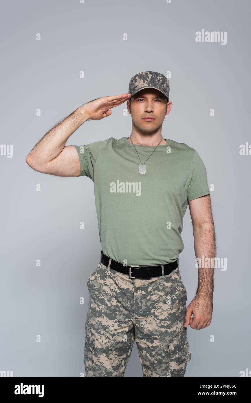 American patriot in t-shirt and military cap saluting during memorial ...