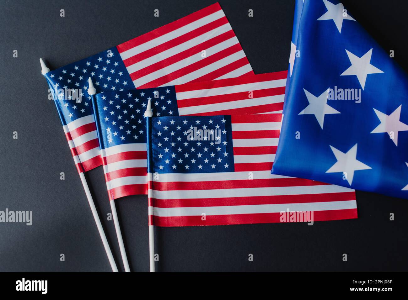 top view of three American flags near folded fabric with stars during ...