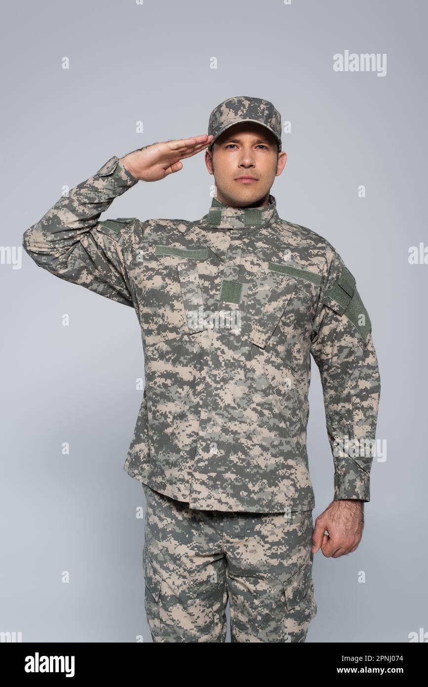 Patriotic army soldier in military uniform with cap saluting during ...