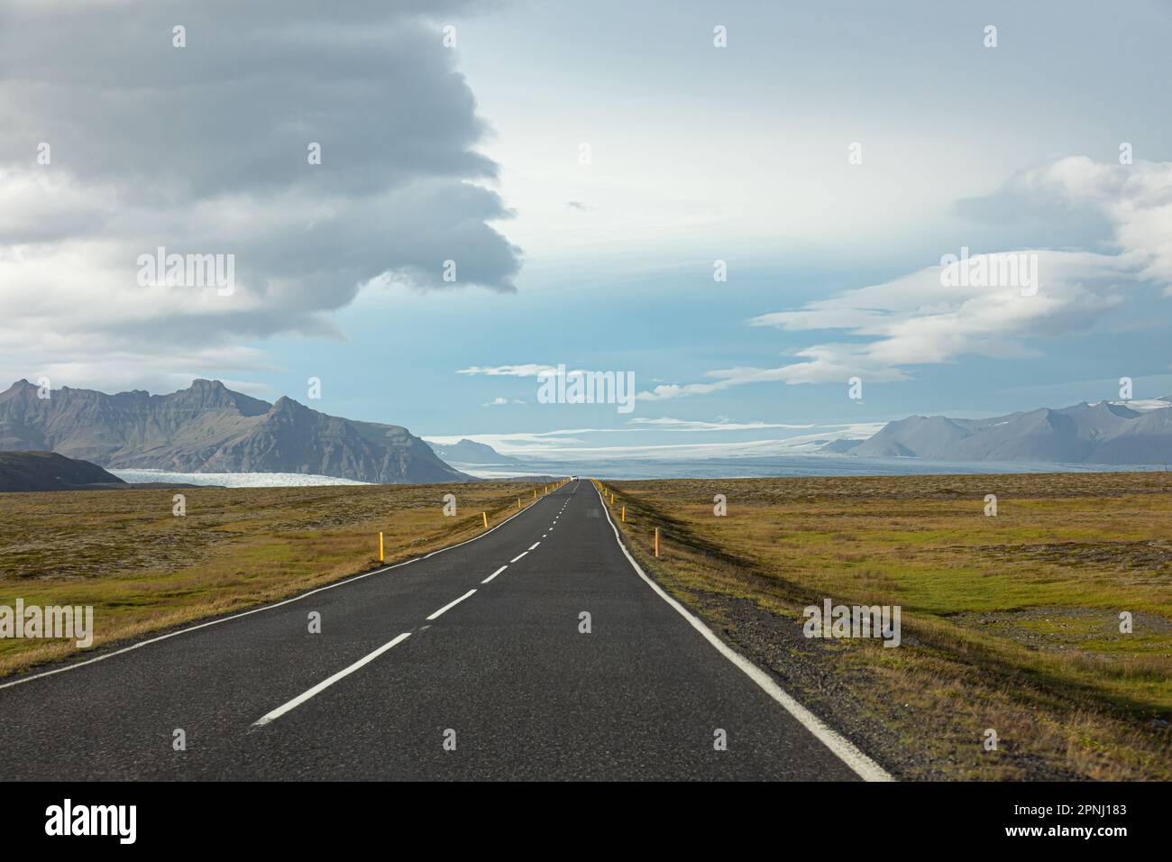 Long and empty road in the countryside with snowy mountains and ...