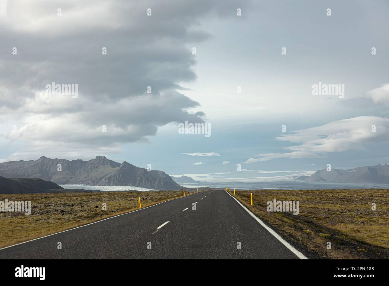 Long and empty road in the countryside with snowy mountains and Vatnajokull glacier on the ...