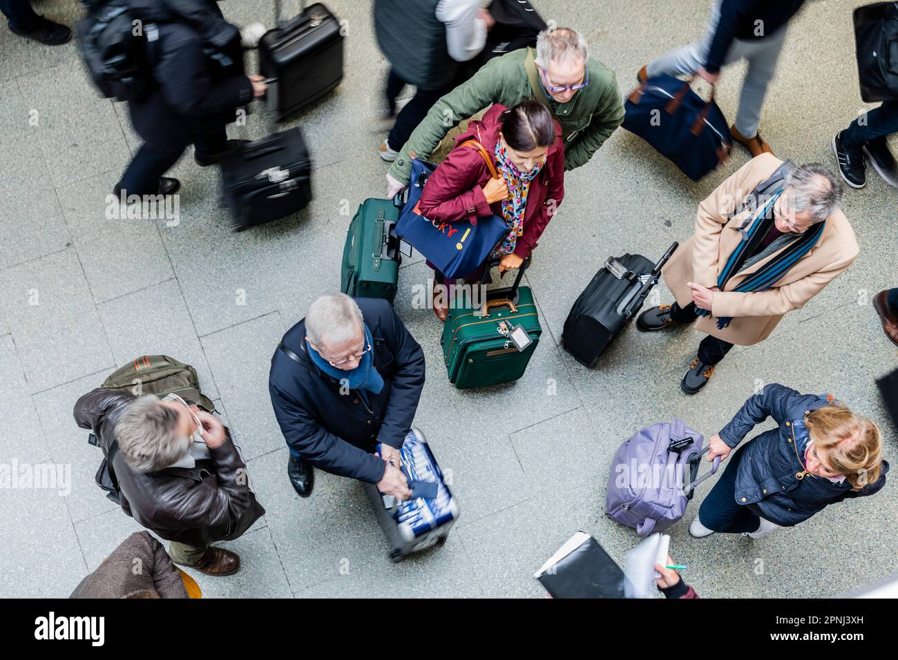 Passengers meeting at train station, listening to group leader at train ...