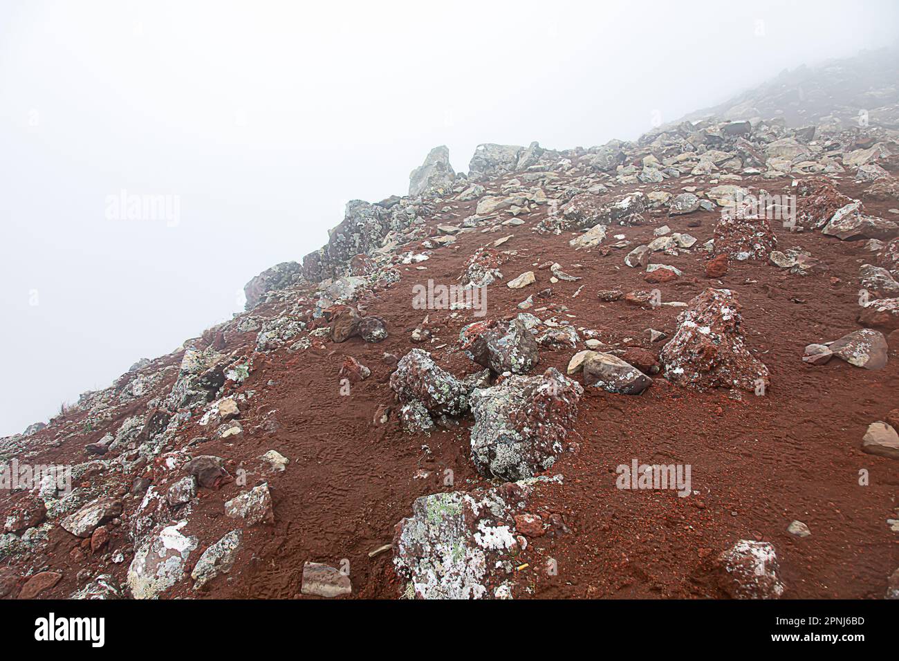 Red soil and rocks on the top of Fagradalsfjall volcano in a foggy day ...