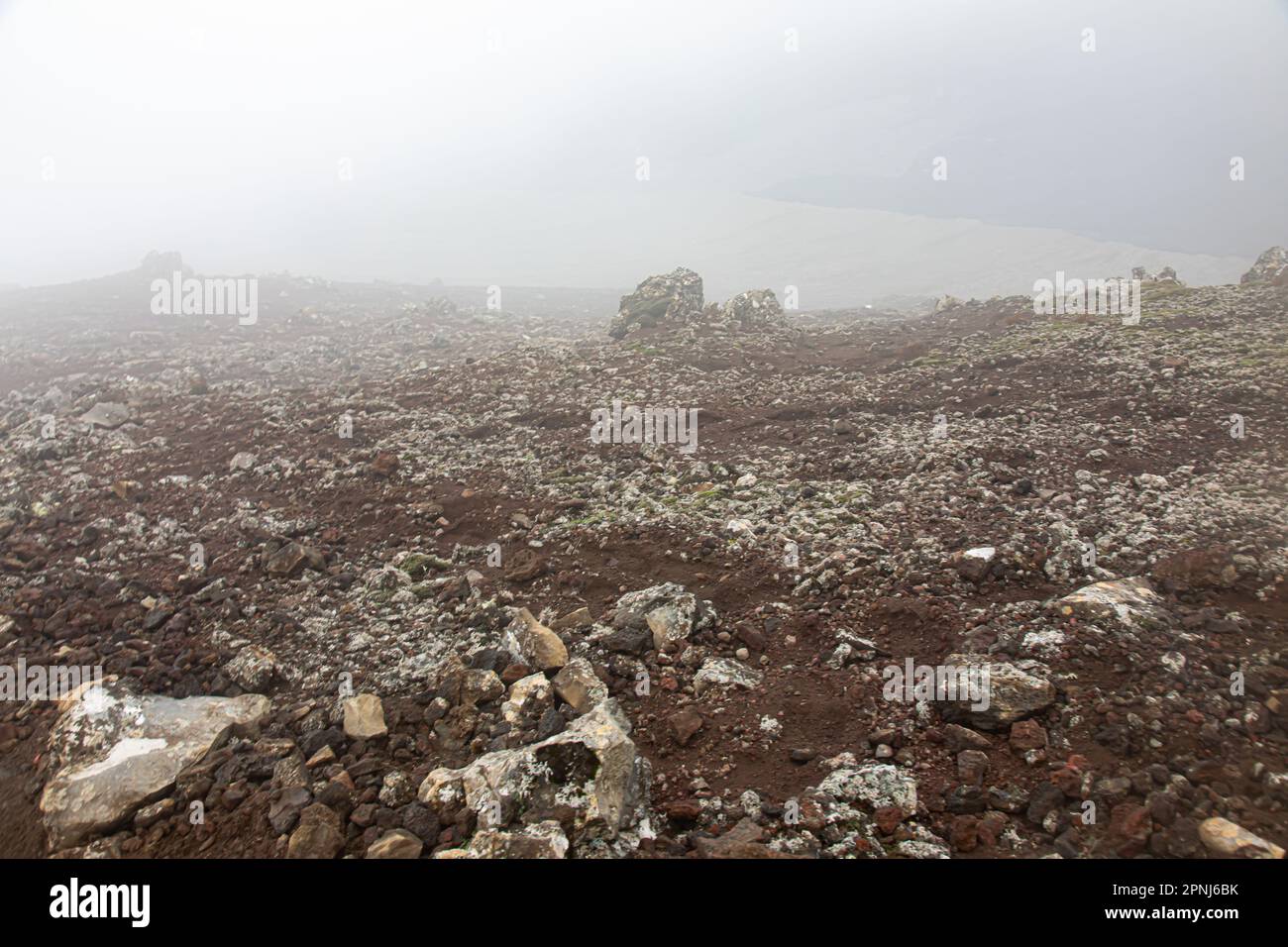 Red soil and rocks on the top of Fagradalsfjall volcano in a foggy day ...