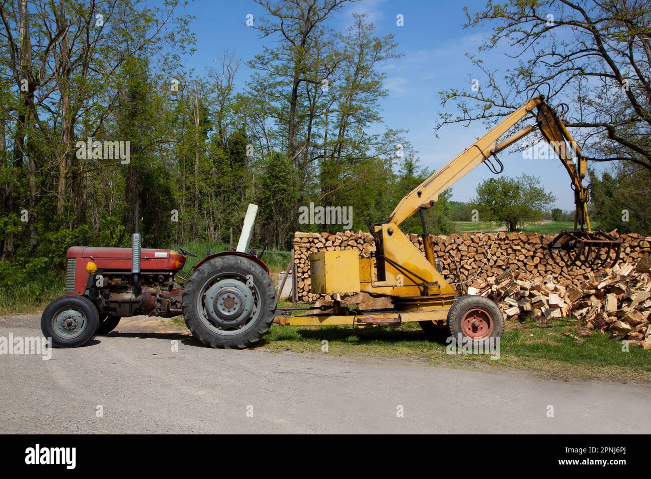 Old agricultural tractor with crane for loading wood log Stock Photo ...