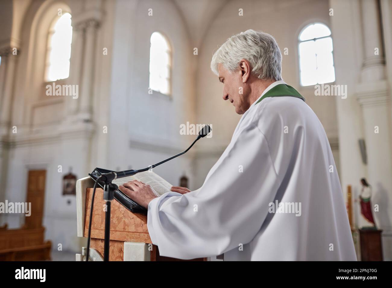 Senior priest reading sermon in microphone standing behind the altar at ...