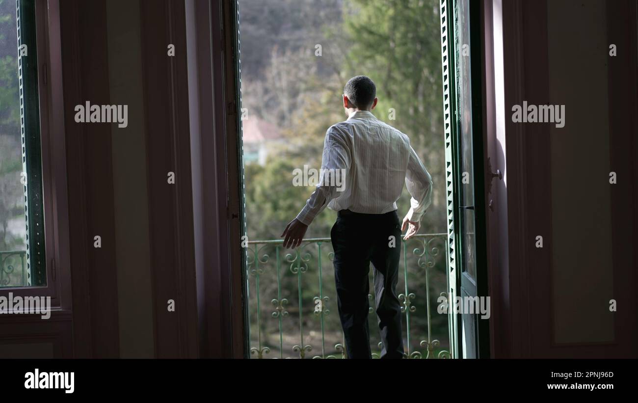 Back view of person opening large windows and stepping out to home ...