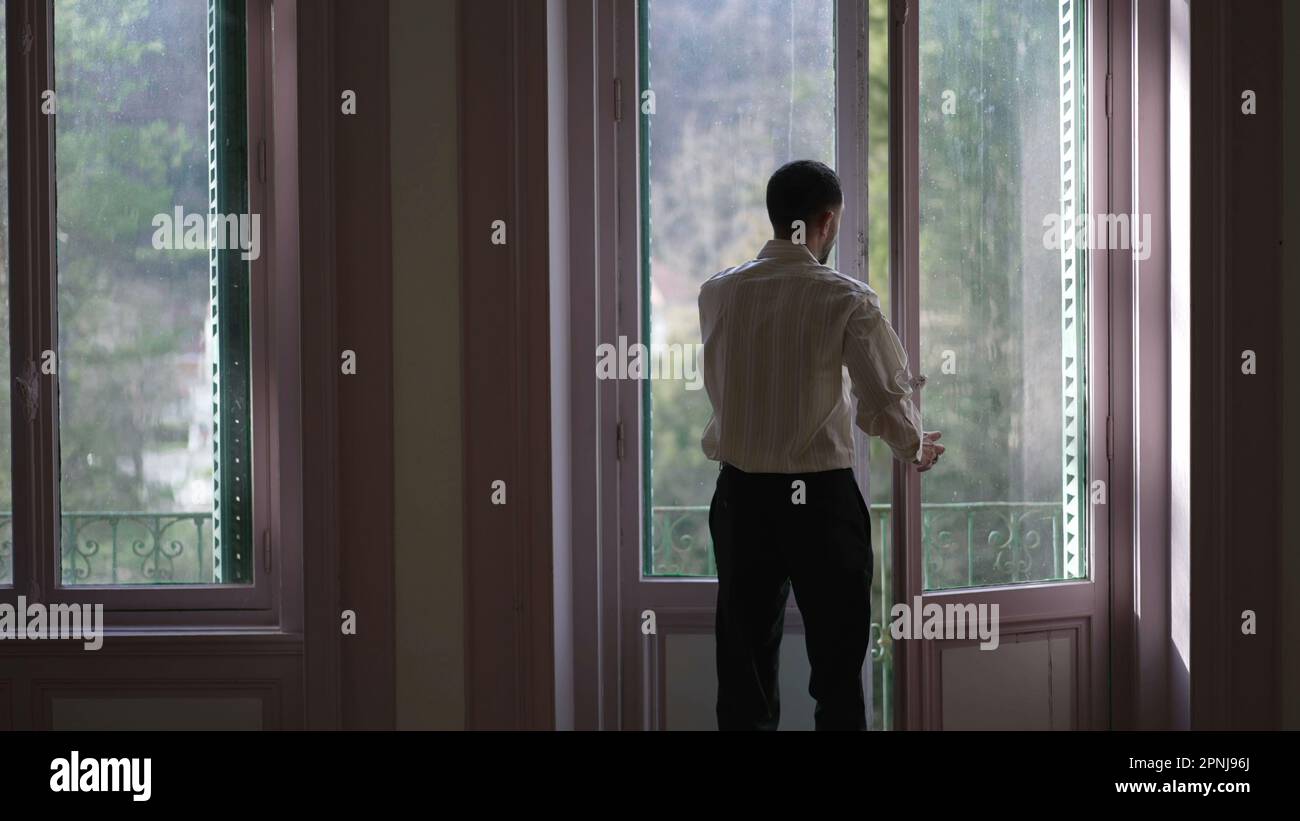 Back view of person opening large windows and stepping out to home ...