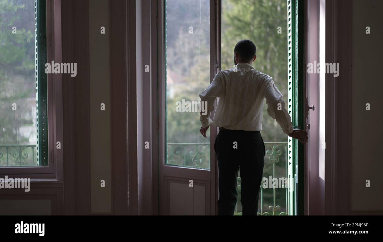 Back view of person opening large windows and stepping out to home ...