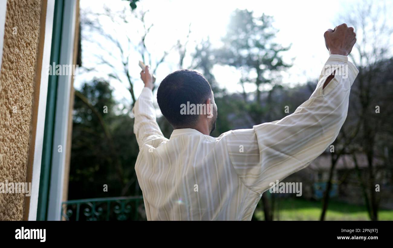 Back of one young man celebrating success while standing outside ...