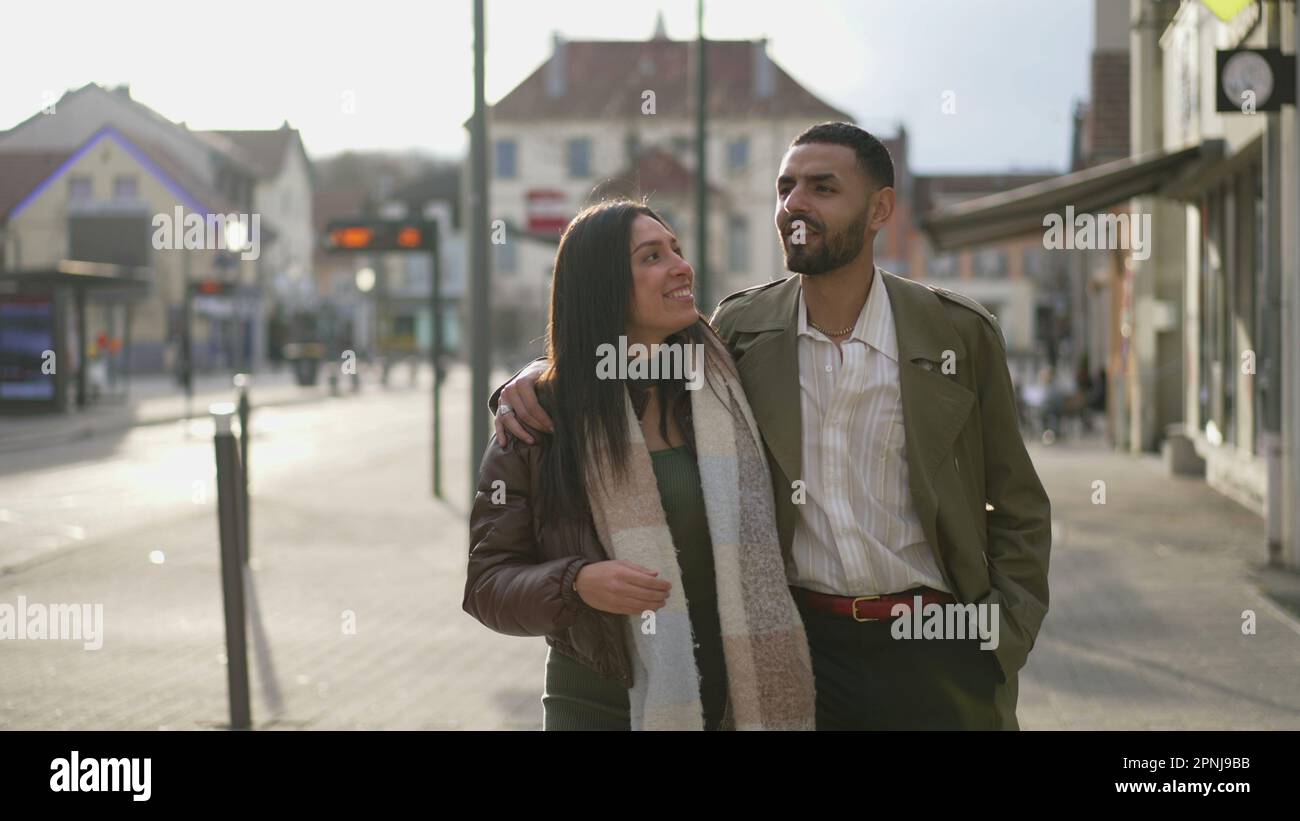 Happy couple walking forward in urban street sidewalk. Tracking shot in ...