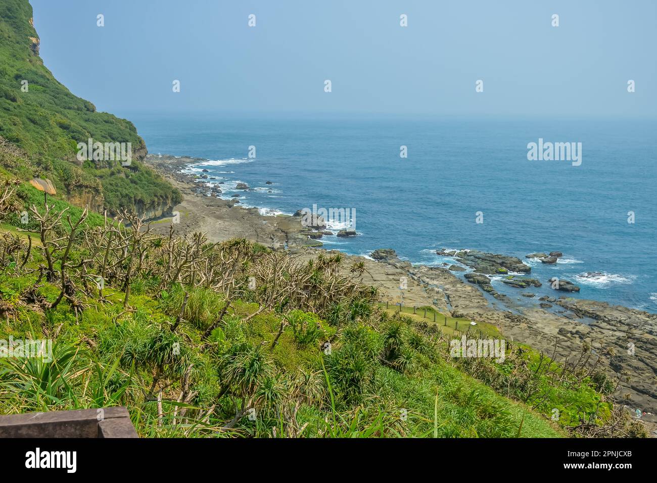 Natural green mountain over the rocky sea shore beach with blue sea ...