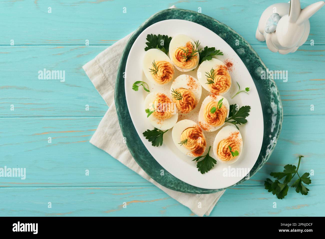 Stuffed or deviled eggs with paprika and parsley on blue plate for ...