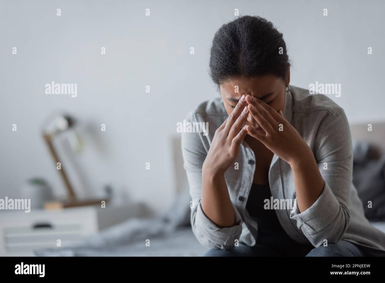 Sad multiracial woman touching face while crying in bedroom,stock image ...