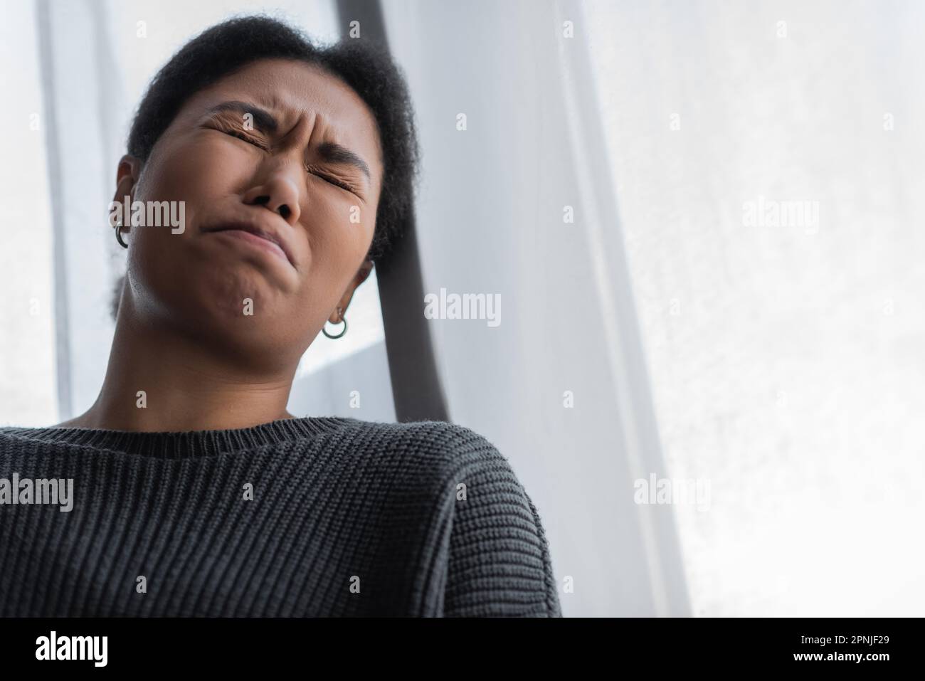 Low angle view of young multiracial woman with depression crying at ...