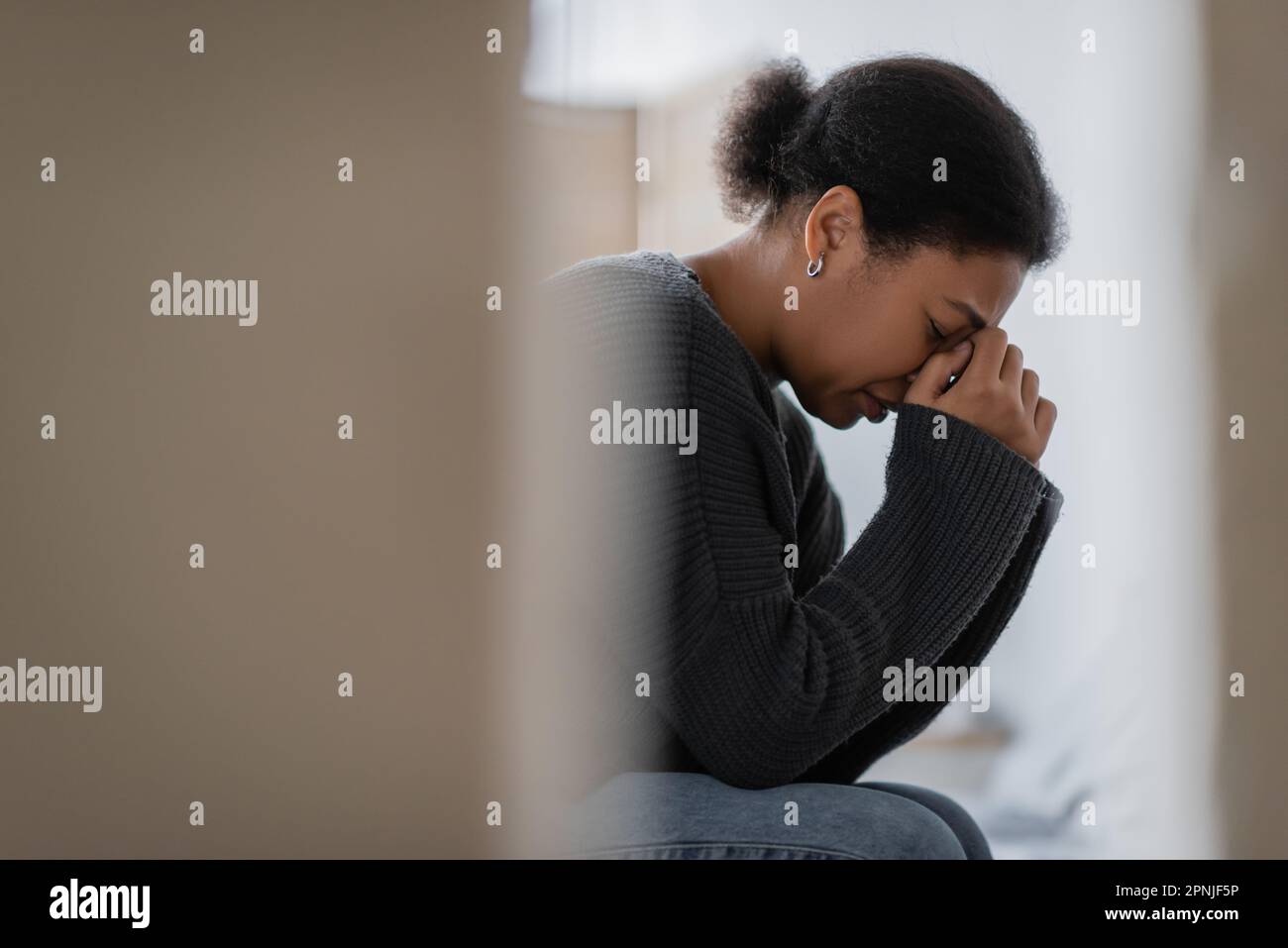 Side view of multiracial woman with mental problem crying at home,stock ...
