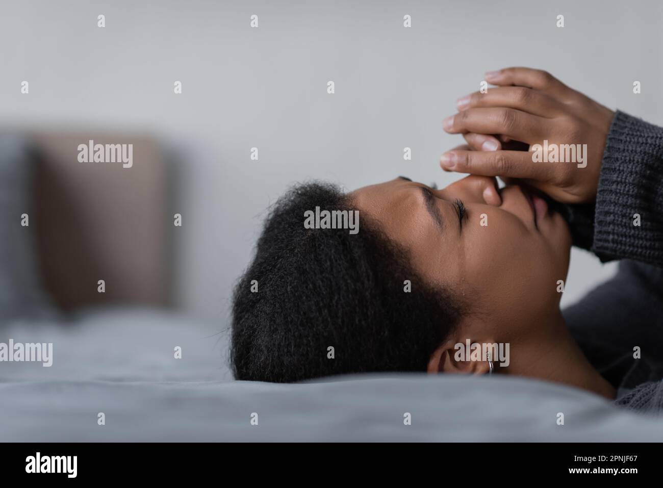 Young multiracial woman with depression crying while lying on bed in ...