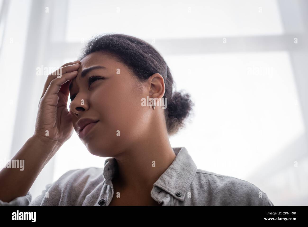 Depressed multiracial woman touching forehead at home,stock image Stock ...